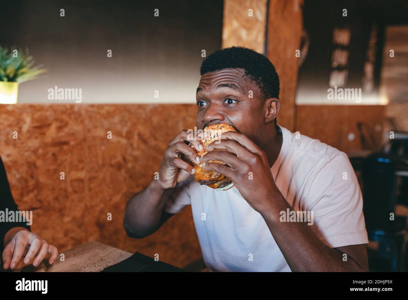 Happy African American male eating yummy burger and enjoying taste ...