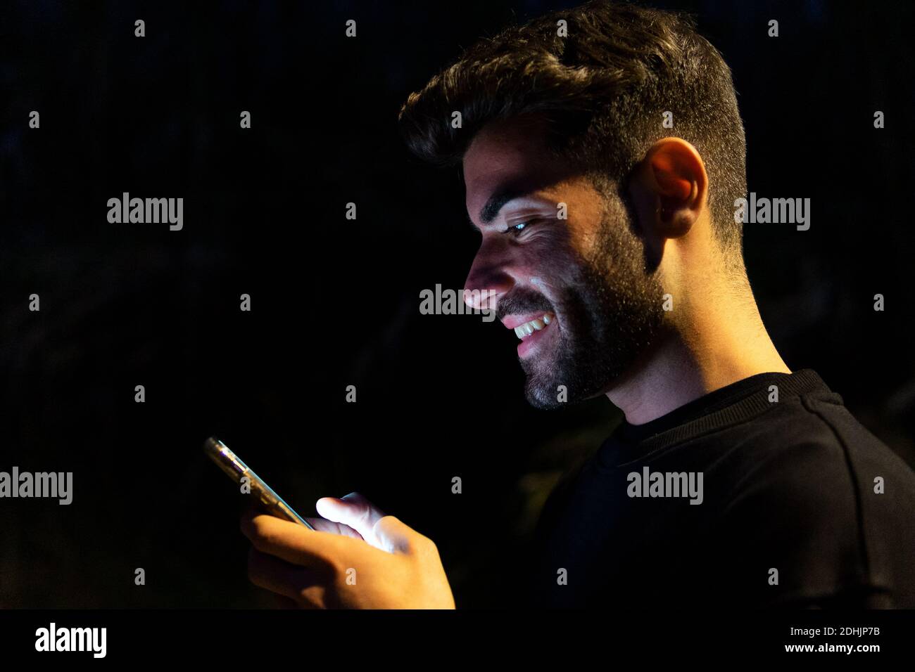 Side view of positive young male browsing smartphone and answering ...