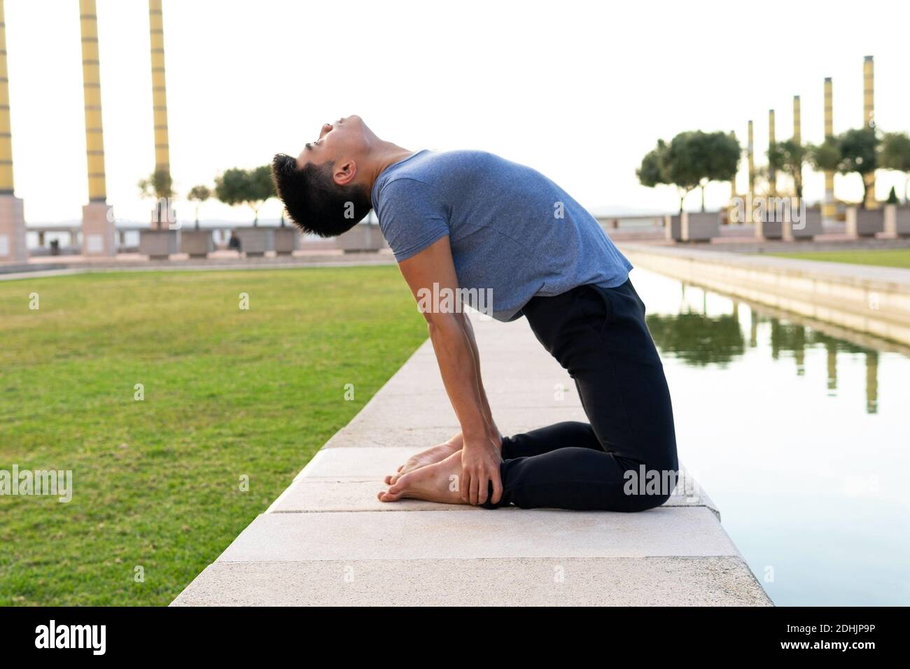 Side view of Asian male in sportswear standing in Ustrasana in backbend ...