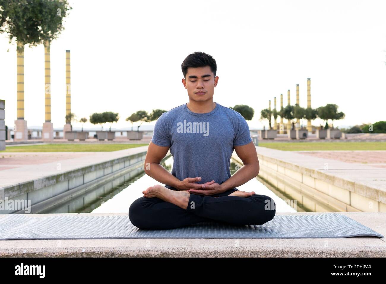 Flexible Asian male sitting on mat in Padmasana and meditating with ...