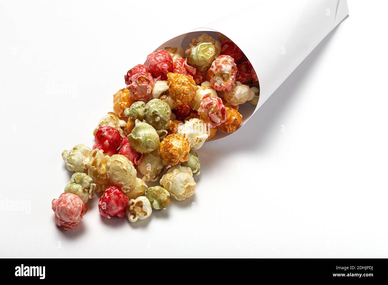 High angle of colorful tasty popcorn in paper cone placed on white ...
