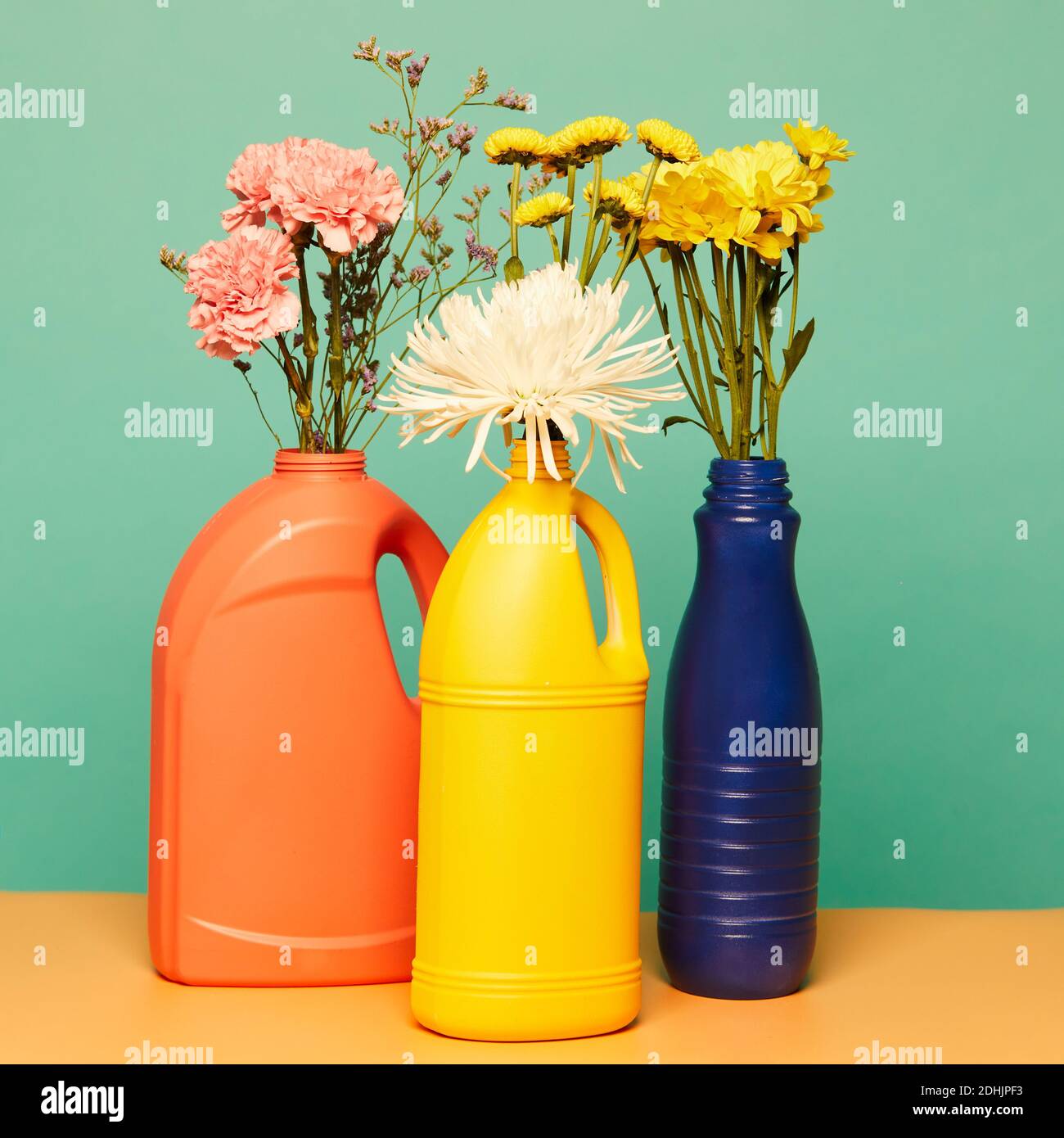 Various blooming flowers placed in colorful plastic bottles from ...