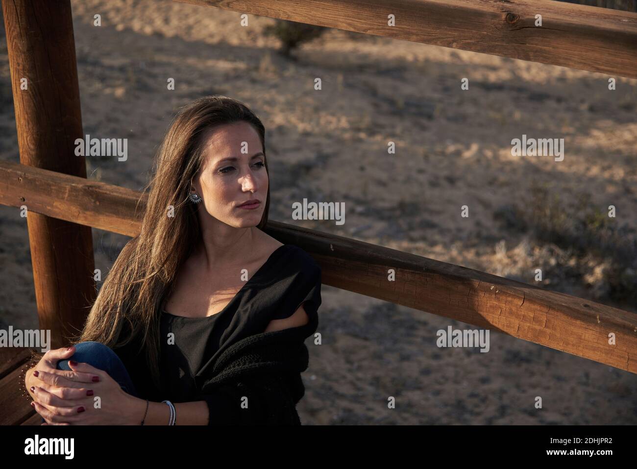 High angle of lonely brunette embracing knee and looking thoughtfully ...