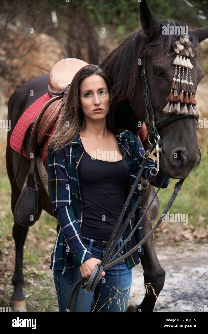 tranquil female equestrian caressing muzzle of chestnut horse while ...