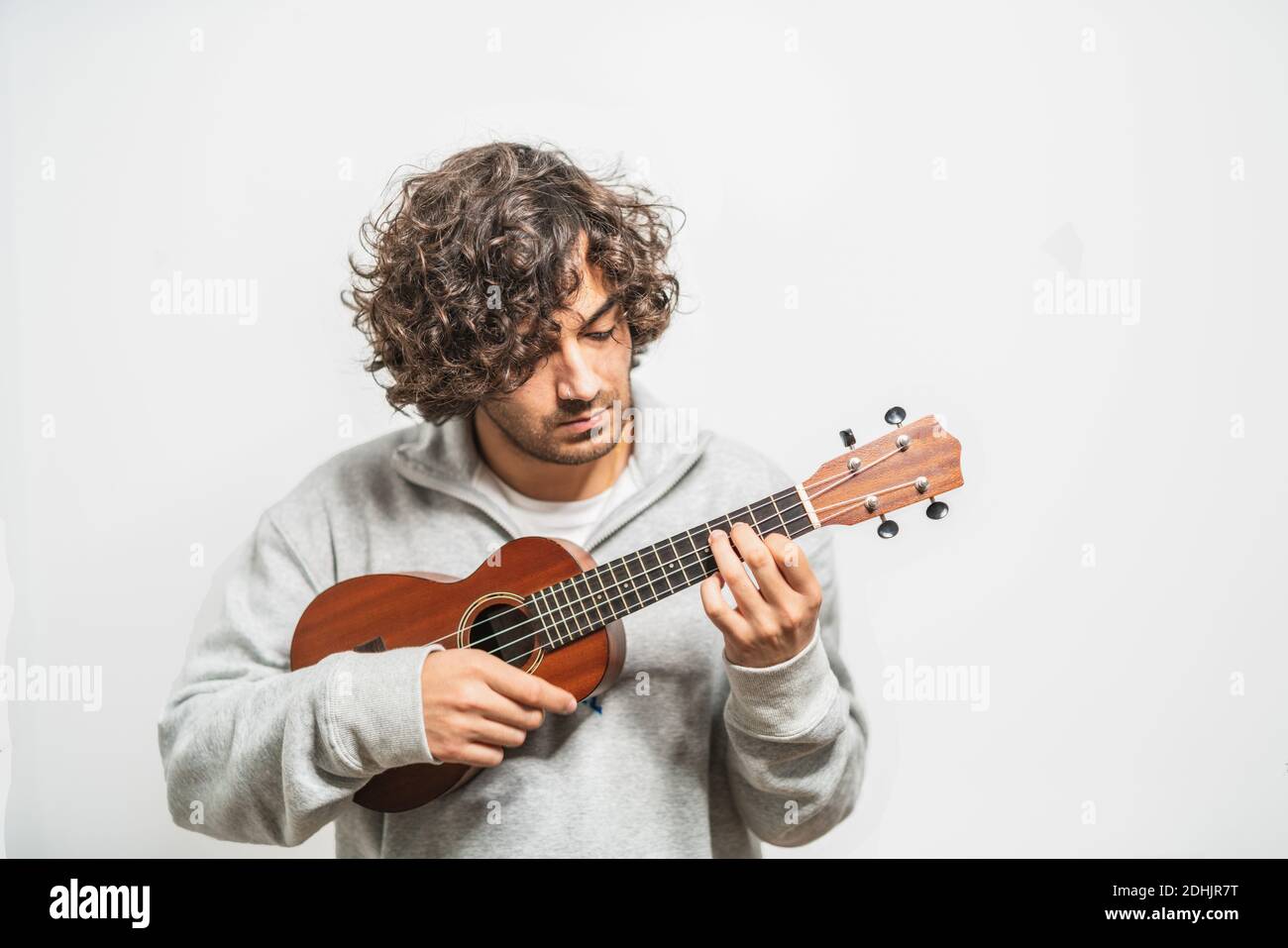 Positive young curly haired ethnic musician in casual wear performing ...