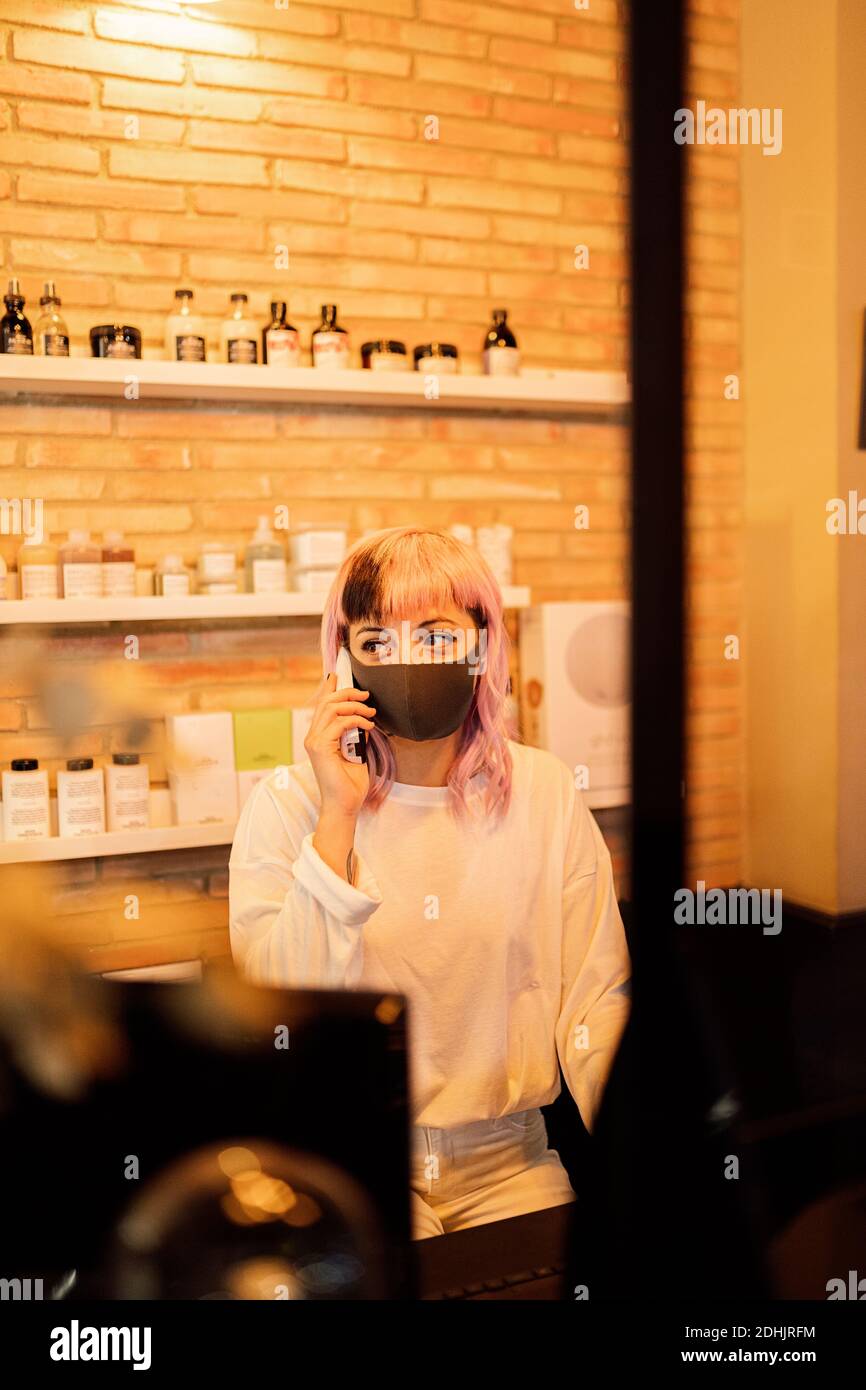 Busy female receptionist standing at counter in barbershop and speaking ...