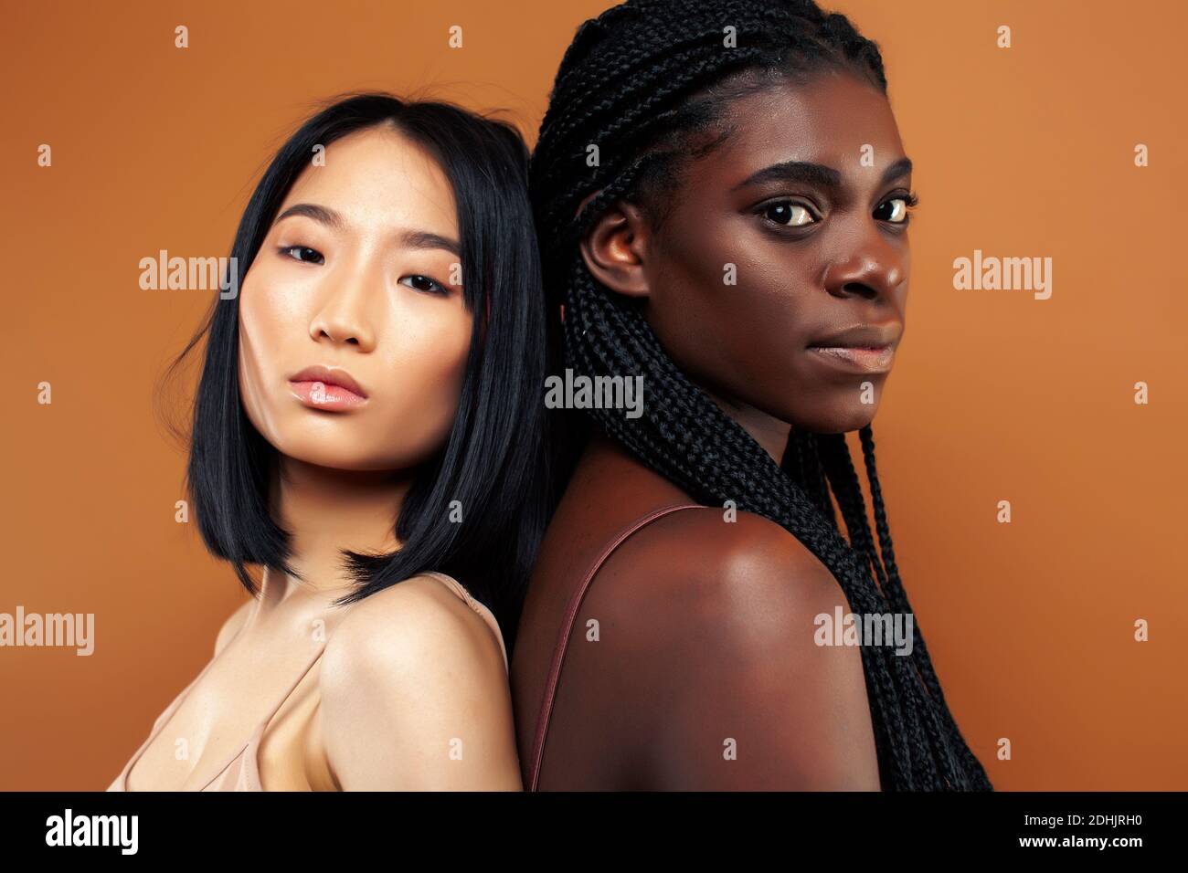 young pretty asian and afro woman posing cheerful together on brown ...