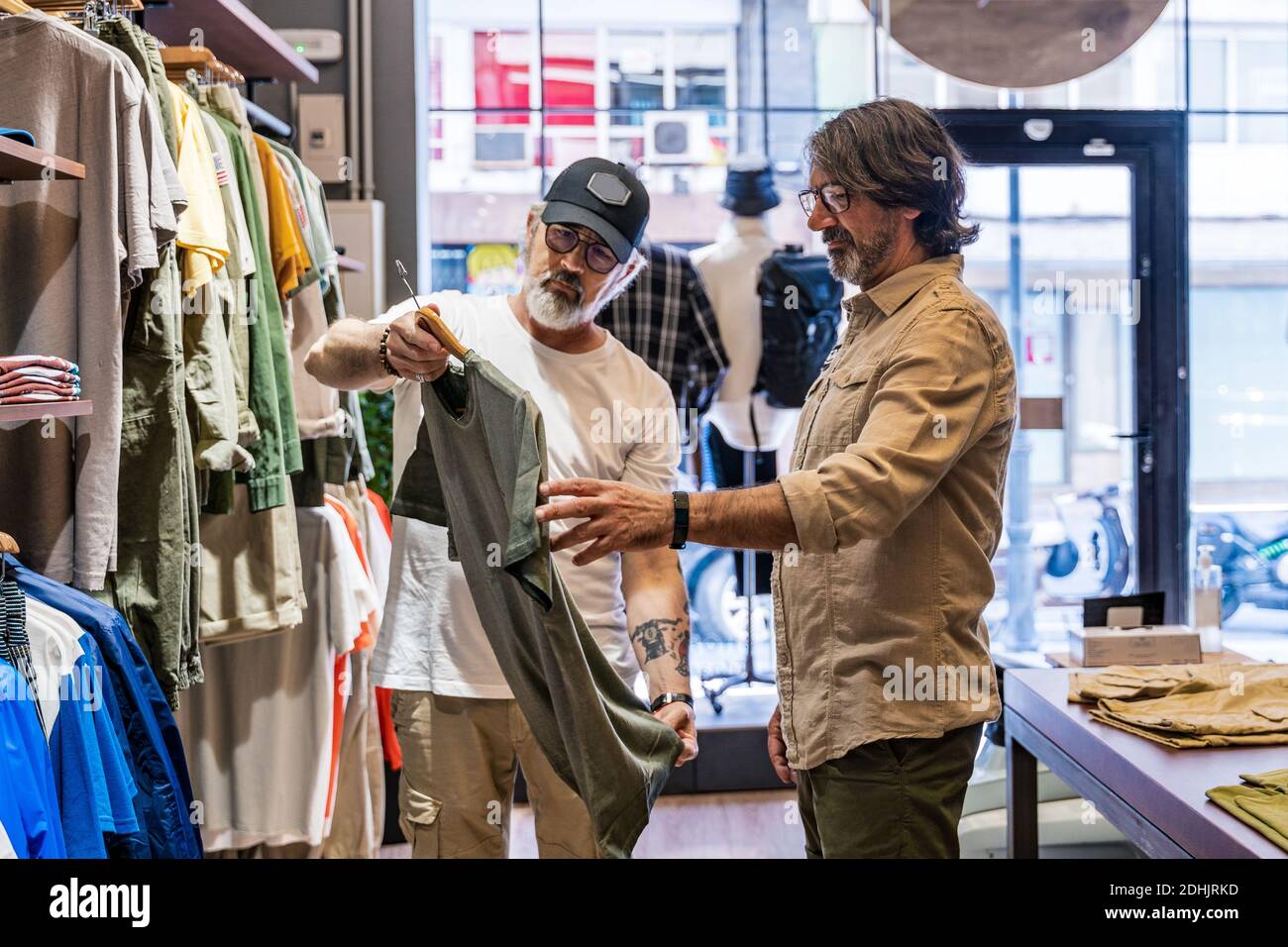 Side view clothing store owner helping new customer to choose a shirt ...