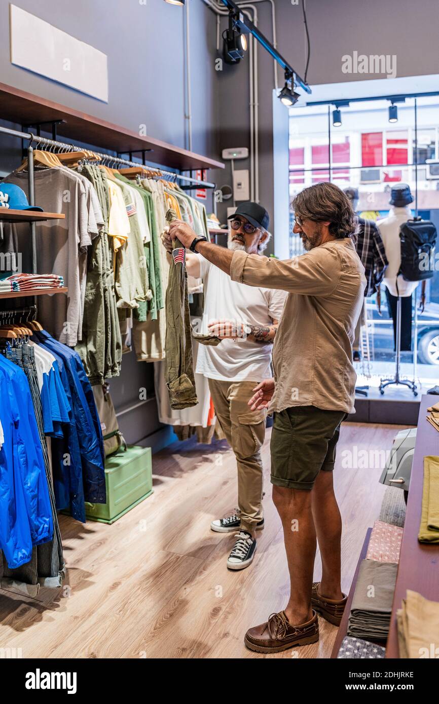 Side view clothing store owner helping new customer to choose a shirt ...