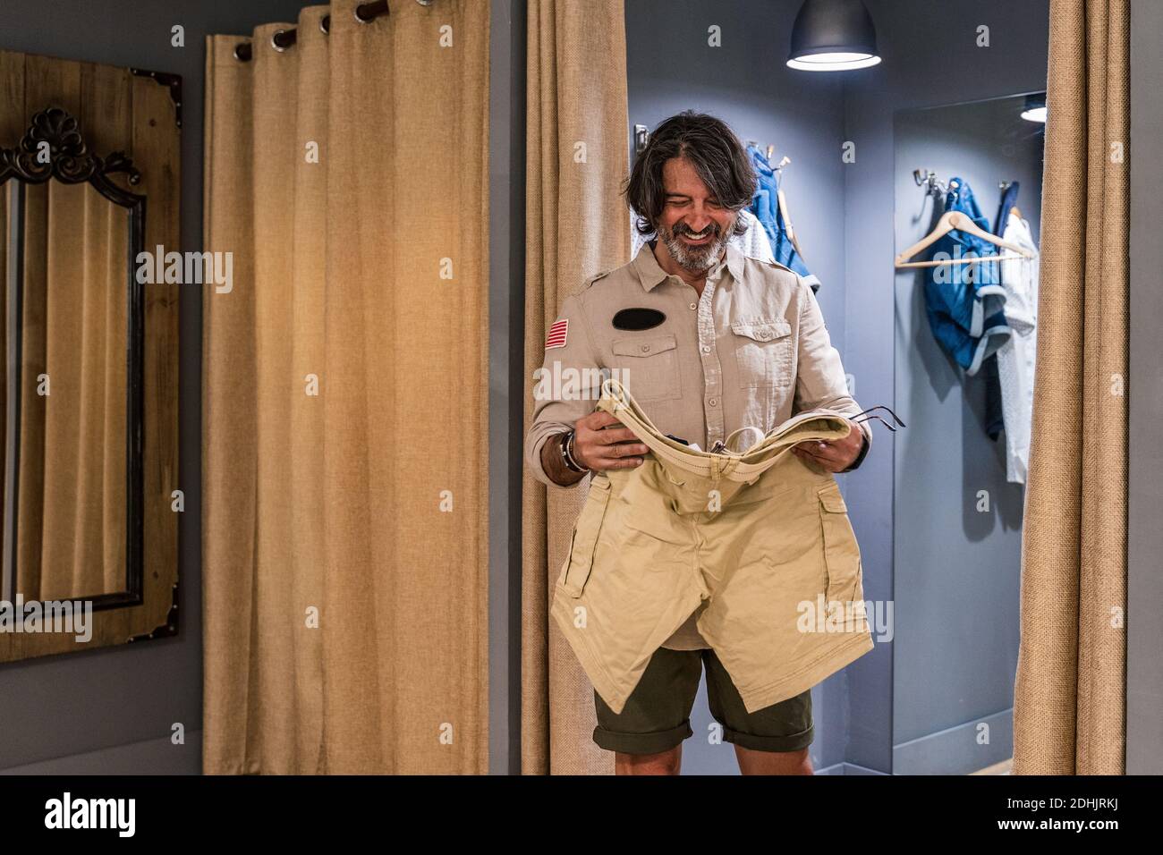 Front view of man checking pants in the clothing fitting room of a ...