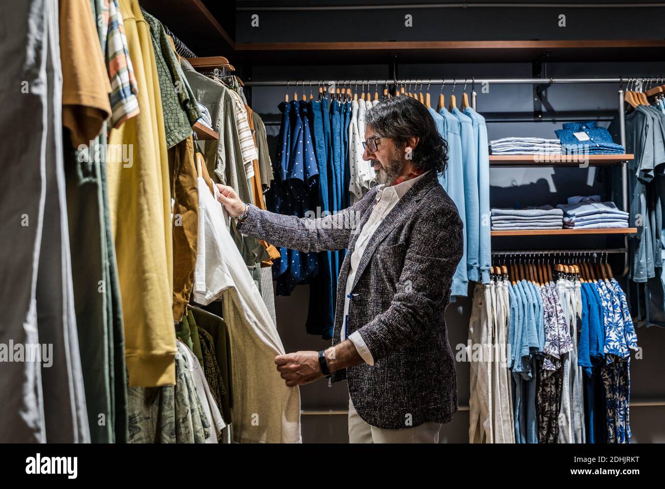 Side view of man choosing clothes in a clothing store Stock Photo - Alamy