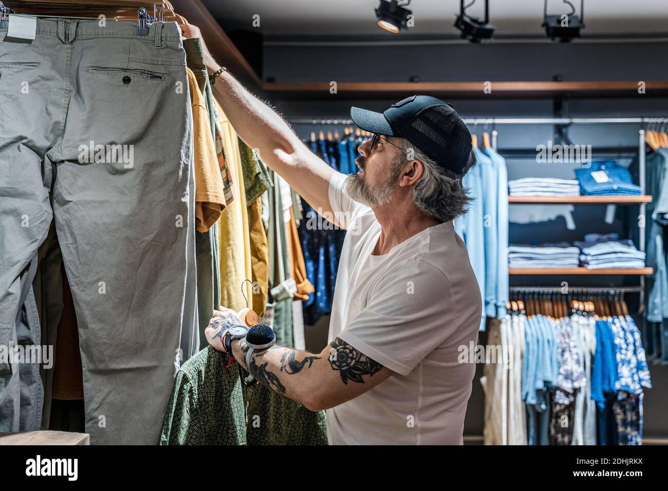 Side view of man choosing clothes in a clothing store Stock Photo - Alamy