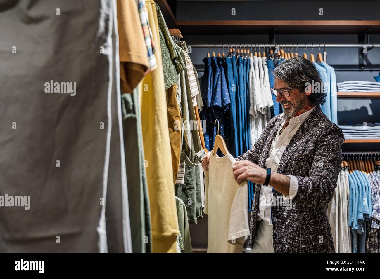 Side view of man choosing clothes in a clothing store Stock Photo - Alamy