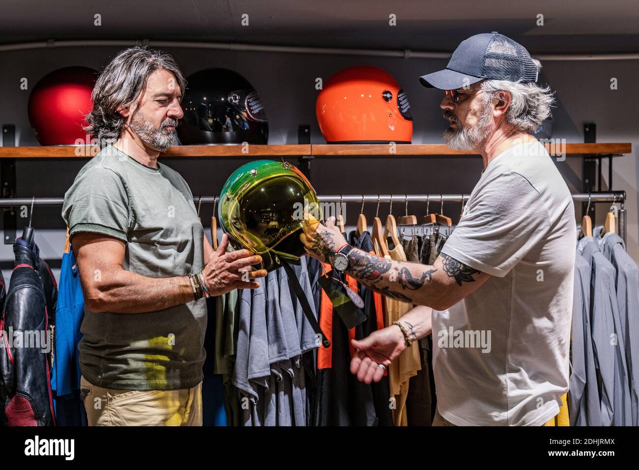 Side view of store owner advising customer on motorcycle helmets Stock ...