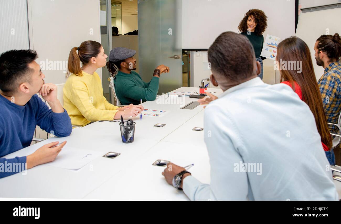 Focused multiracial coworkers sitting around table listening to female ...