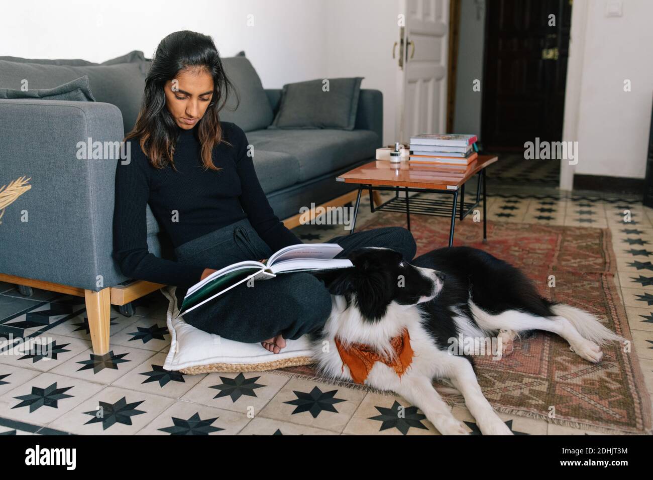 Thoughtful Indian female reading interesting story in book and sitting ...