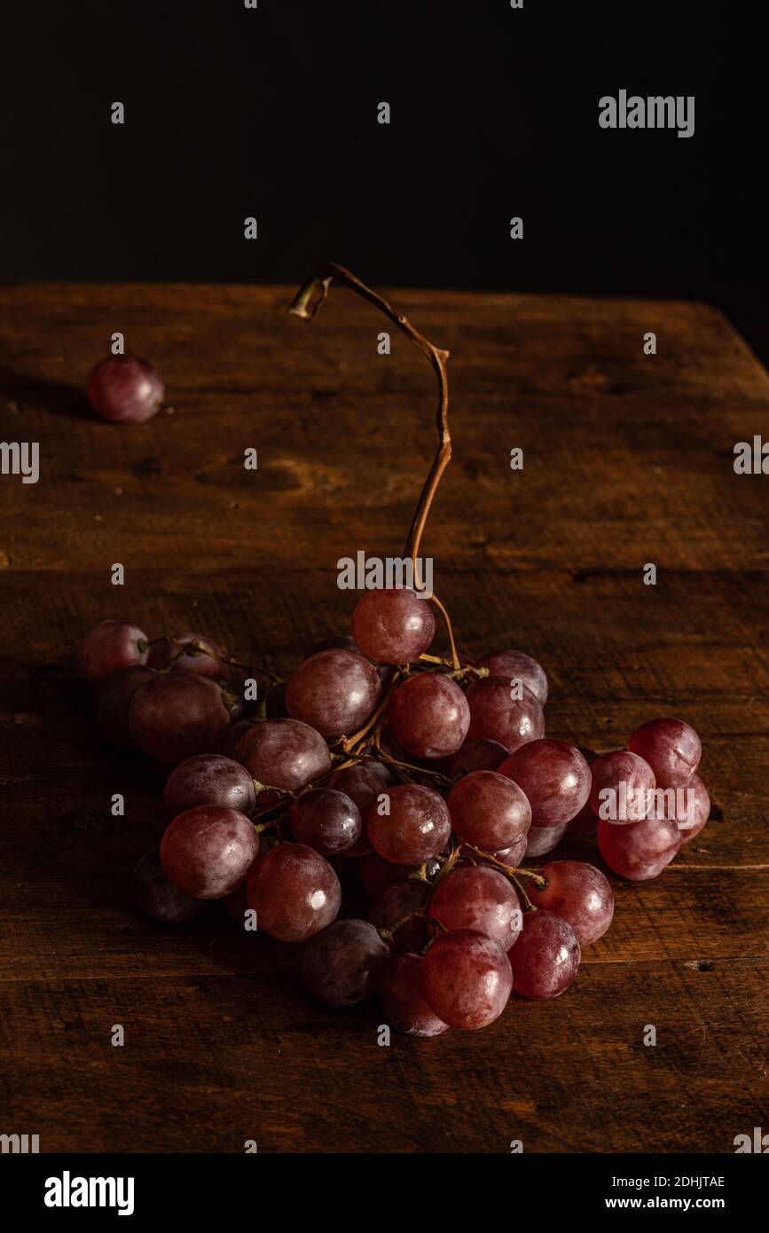 High angle of bunch of fresh ripe juicy red grapes placed on rustic ...