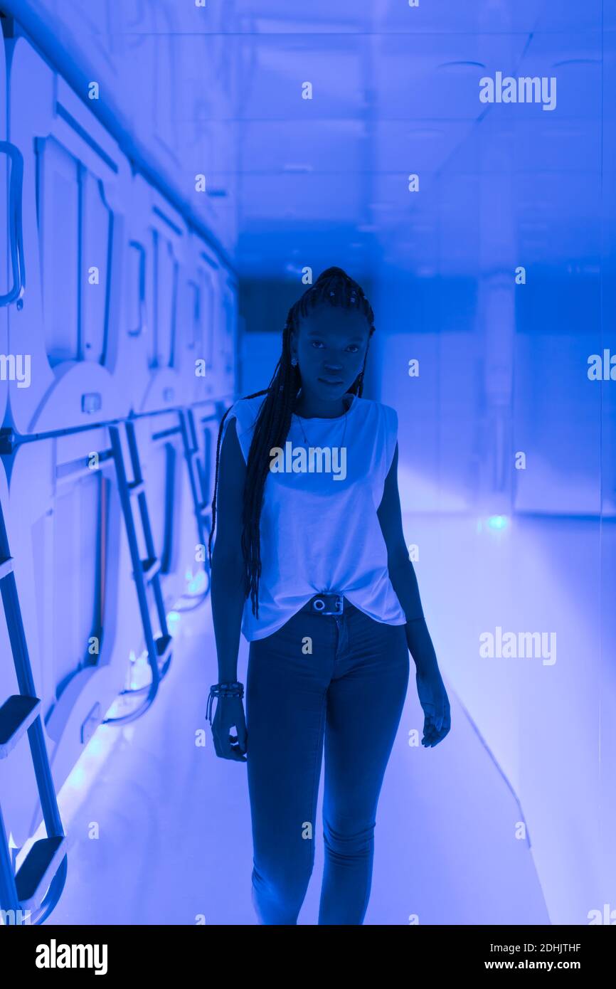 Young African American Woman standing in narrow passage between rows of ...