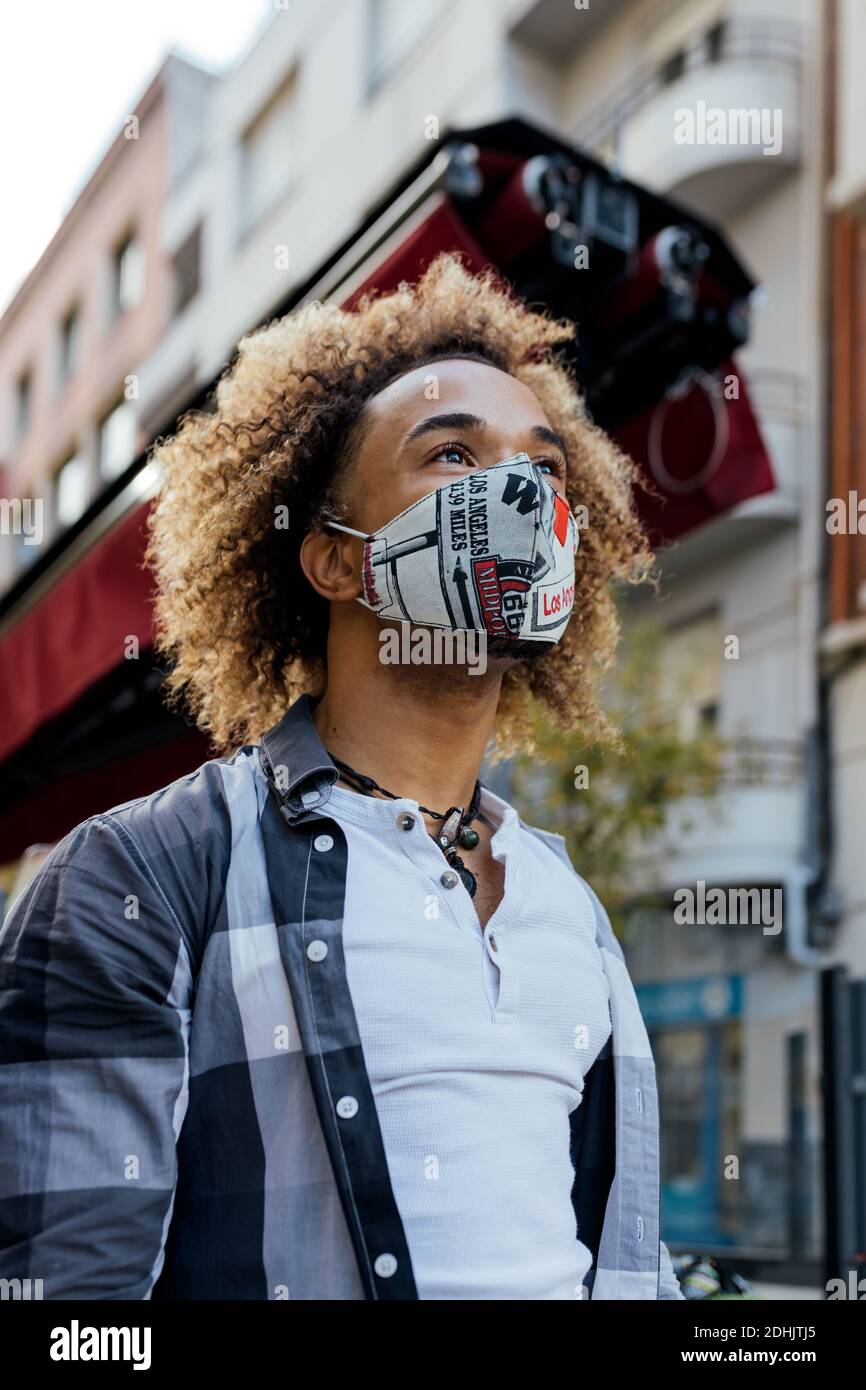 From below modern stylish African American male with curly hair dressed ...