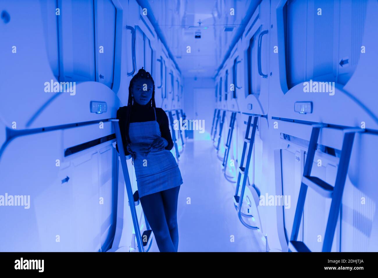 Young African American Woman standing in narrow passage between rows of ...