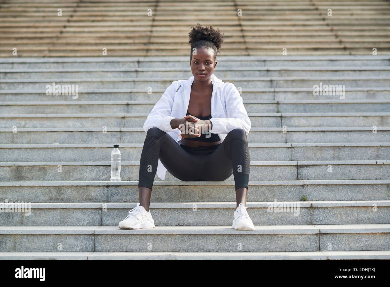 Relaxed African American female runner sitting on stairs in city ...