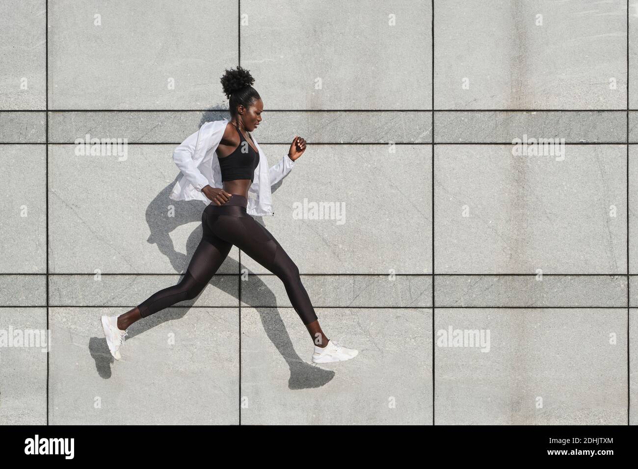 Side view of fit African American female athlete jumping above ground ...