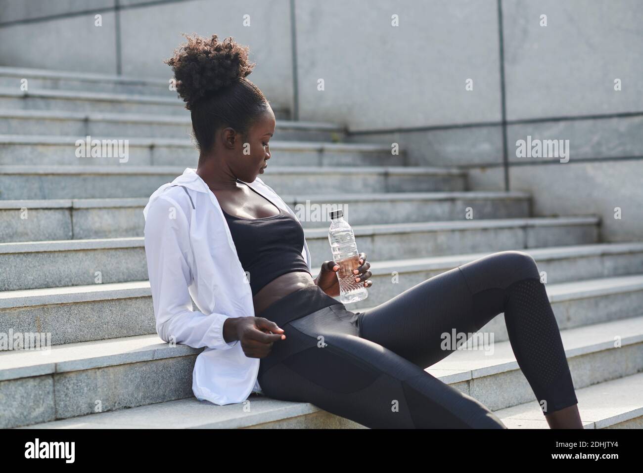Side view of relaxed African American female runner sitting on stairs ...