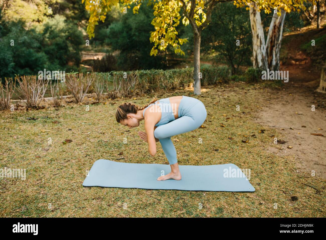 Full body side view of young slim female performing One Legged Chair ...