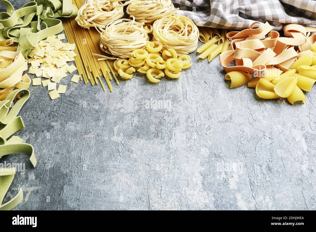 Mixed types and shapes of italian pasta on grey stone, background. Copy ...