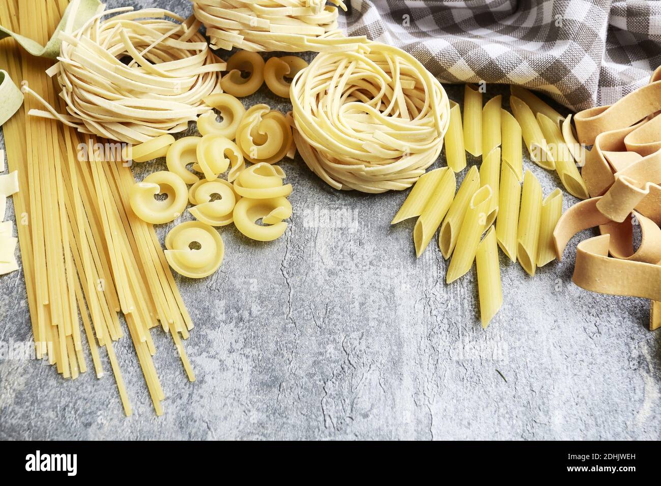 Mixed types and shapes of italian pasta on grey stone, background. Copy ...