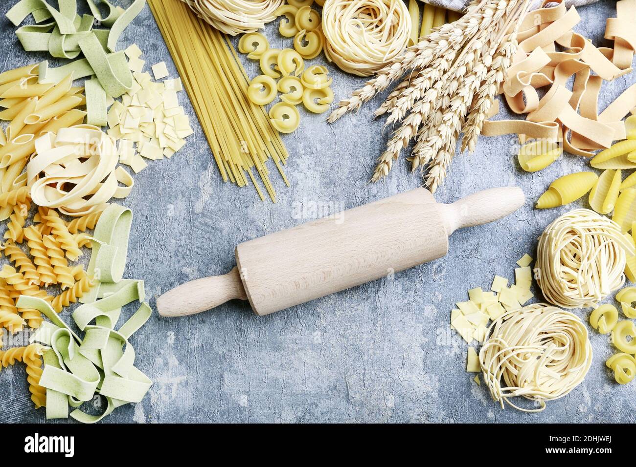 Mixed types and shapes of italian pasta on grey stone, background. Copy ...