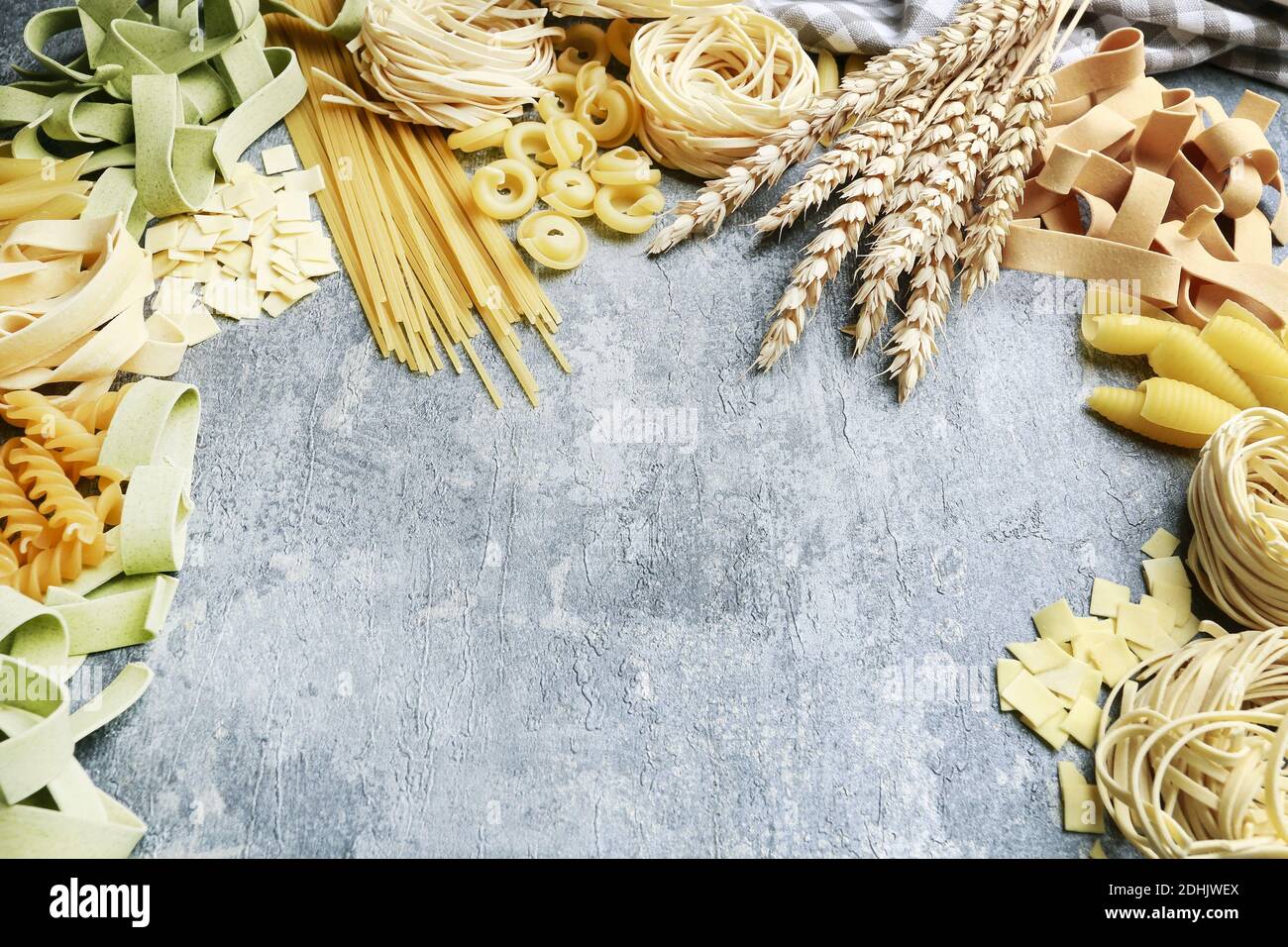 Mixed types and shapes of italian pasta on grey stone, background. Copy ...