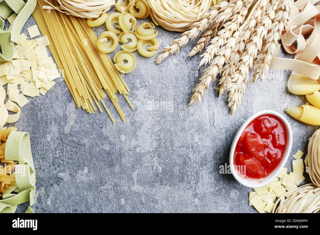 Mixed types and shapes of italian pasta on grey stone, background. Copy ...