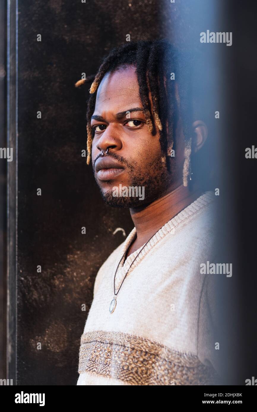 Side view of frowning modern African American guy with dreadlocks ...