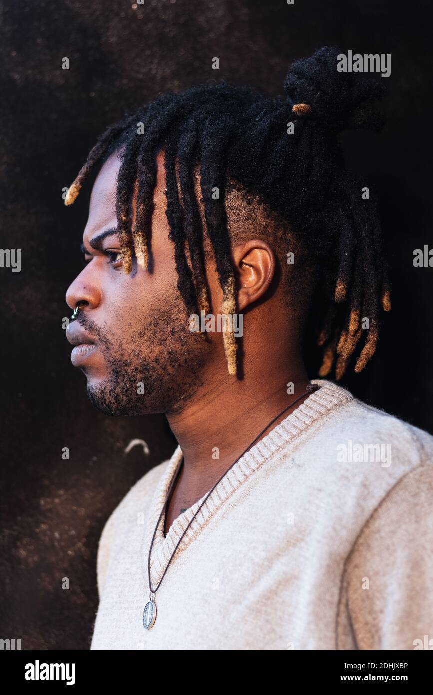 Side view of frowning modern African American guy with dreadlocks ...