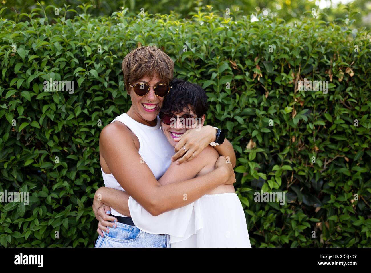 Adult friendly women cuddling in green park while smiling sincerely and ...