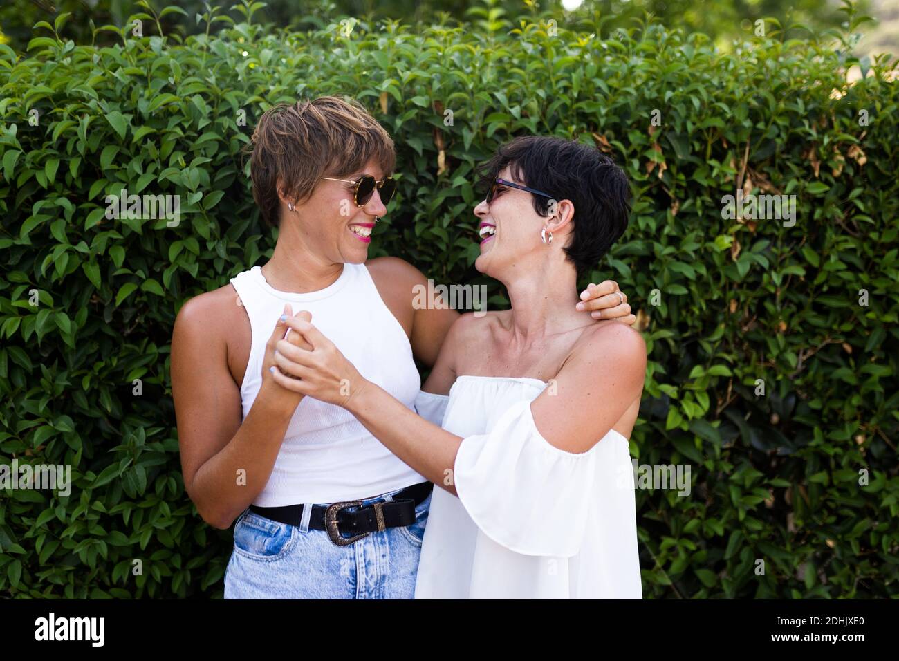 Adult friendly women cuddling in green park while smiling sincerely ...