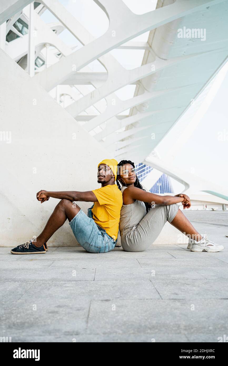 Side view of cool African American male and female friends sitting back ...