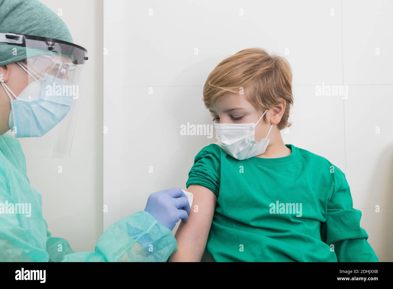 Side view of medic in protective costume disinfecting skin of patient ...