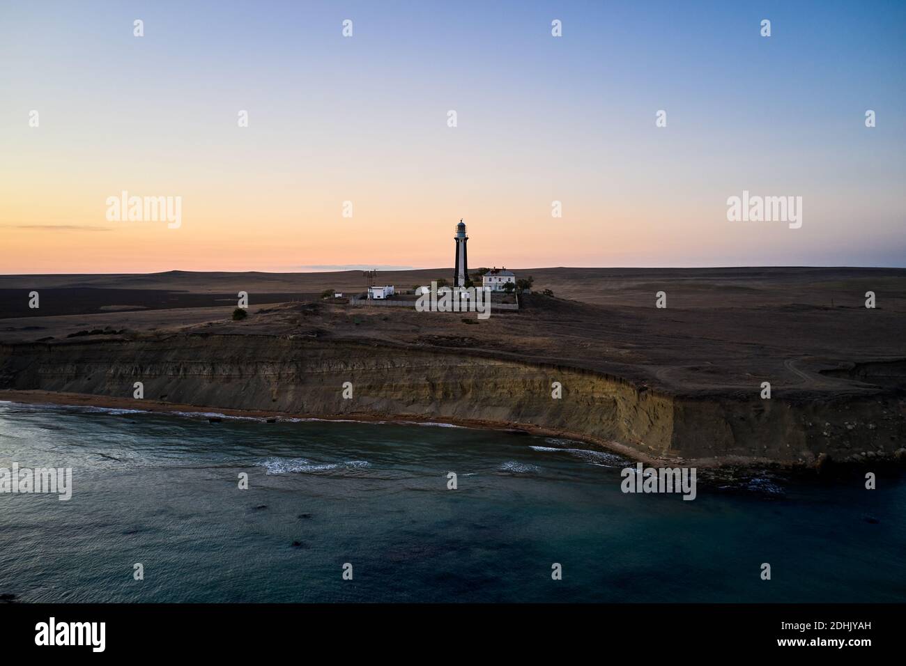 Tower of white beacon located on coast near waving sea under overcast ...