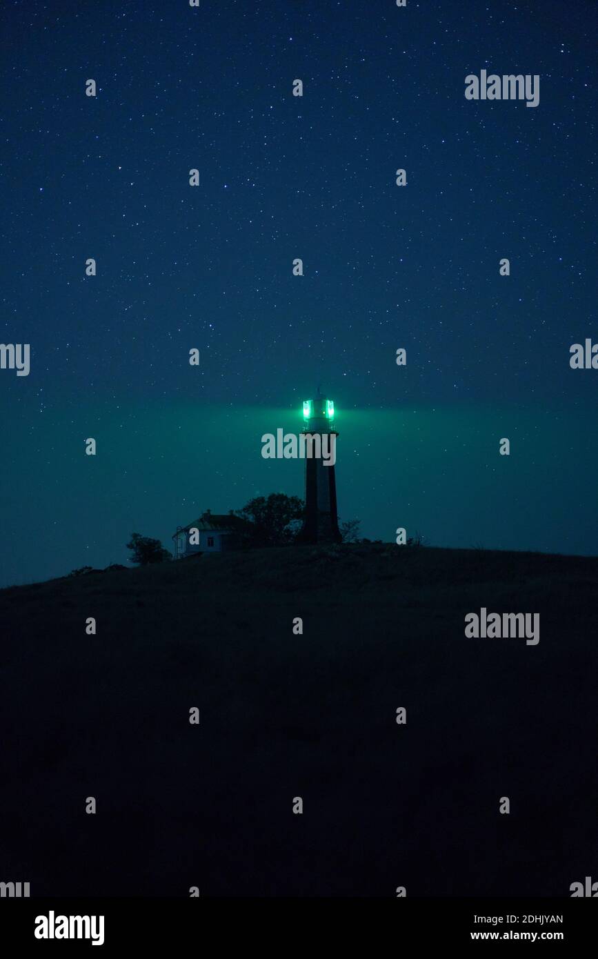 Beacon tower located on hill and illuminating darkness with green light ...