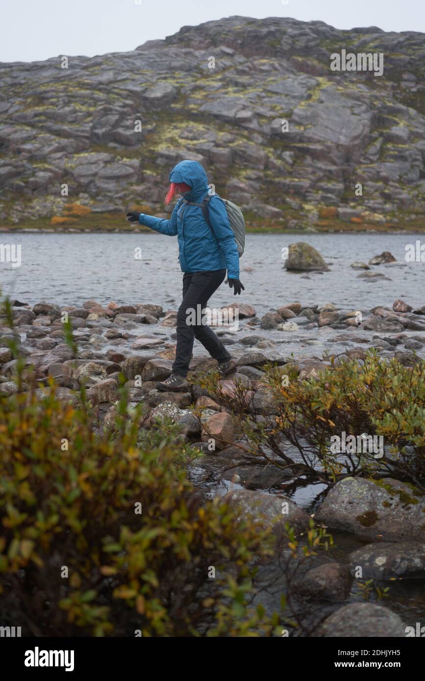 Side view of female explorer in warm clothes crossing river while ...