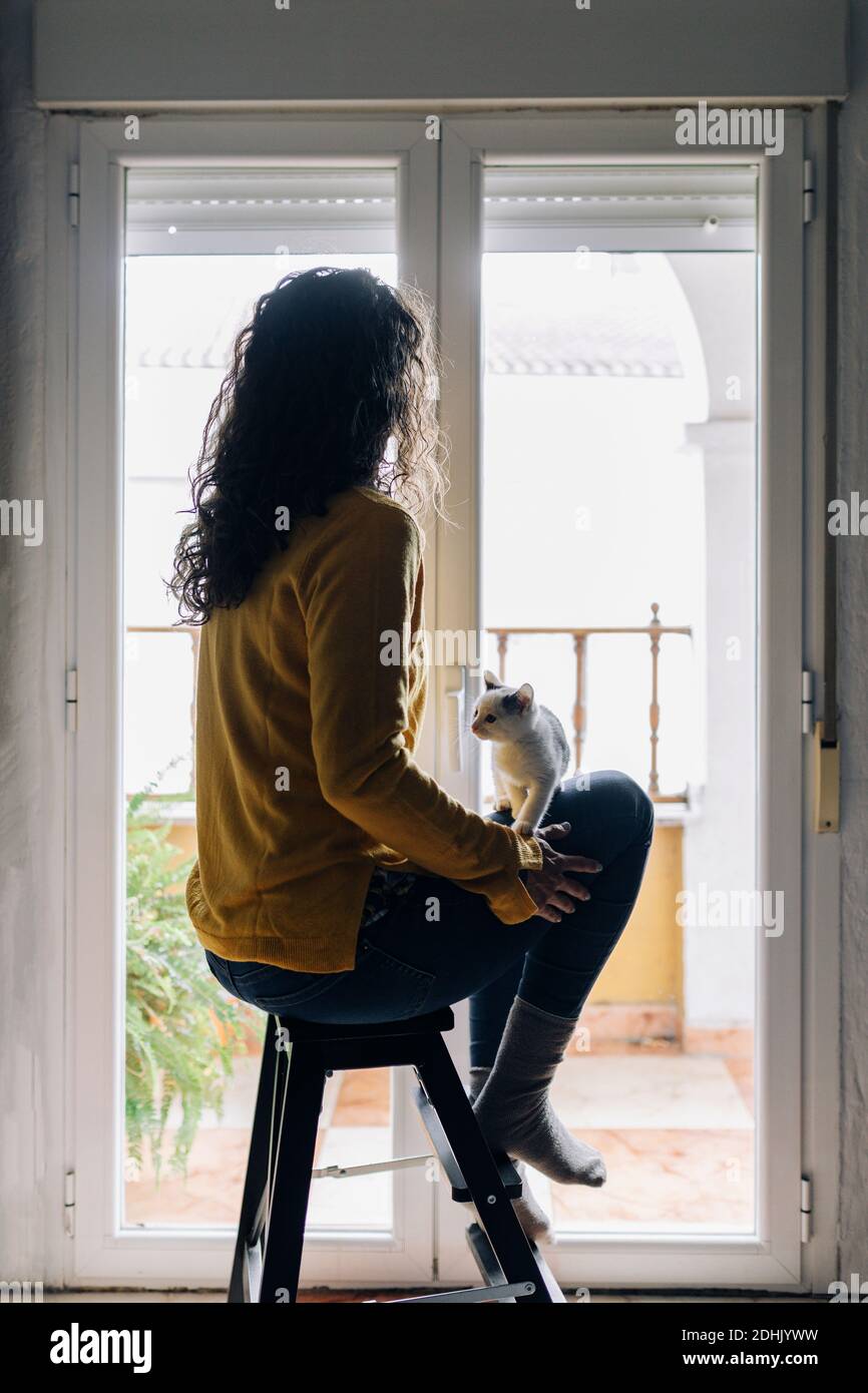 Full body side view of tranquil female in casual clothes sitting on ...