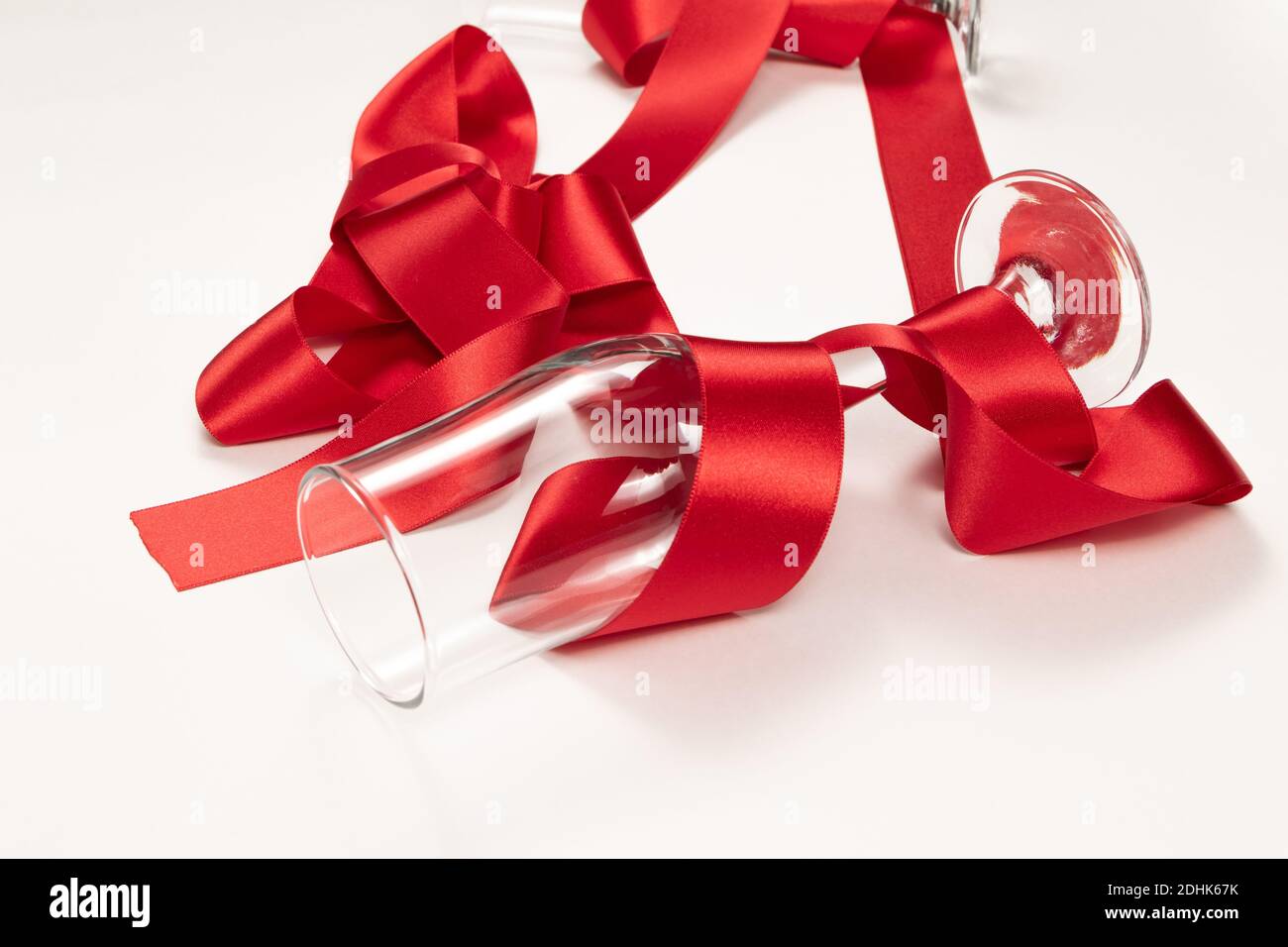 two glasses wrapped in a red satin ribbon lie on a white background ...
