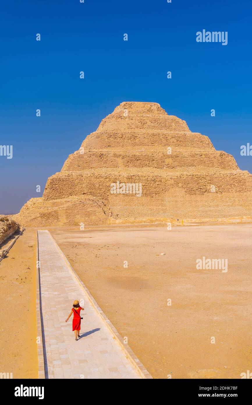 A vertical shot of a tourist walking towards the Pyramid of Saqqara ...