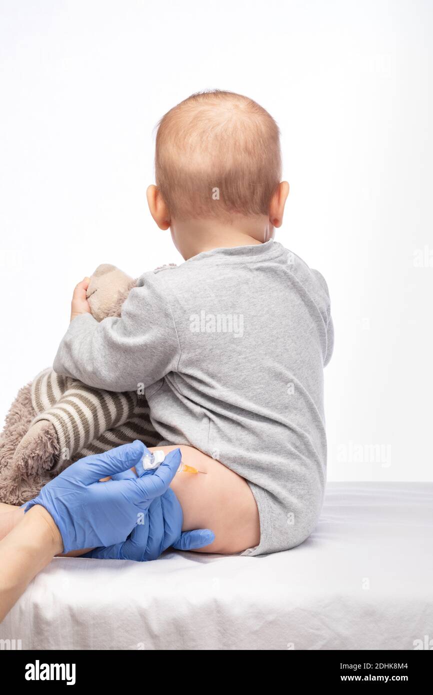 Pediatrician or nurse giving an intramuscular injection of a vaccine to ...