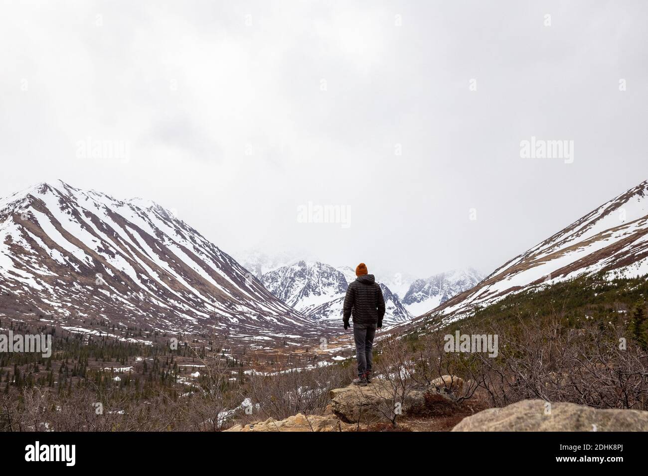 A beautiful shot of a hiker standing on rock, to look at snowy ...