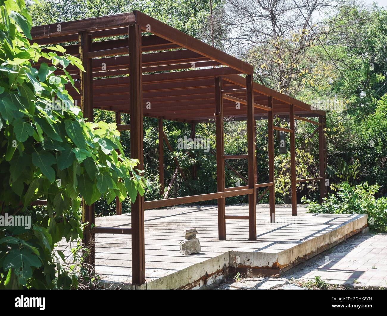 A metal structure standing on a concrete slab among the trees ...
