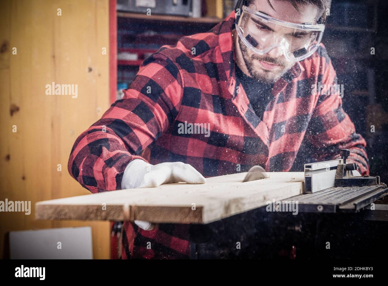 A young male carpenter at work with wooden plank in a carpentry Stock ...