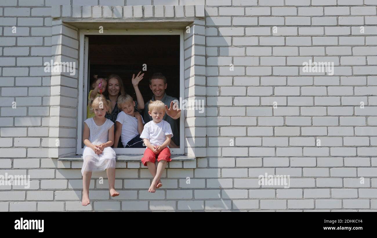 A large family waves their hands and hides from the window of their ...